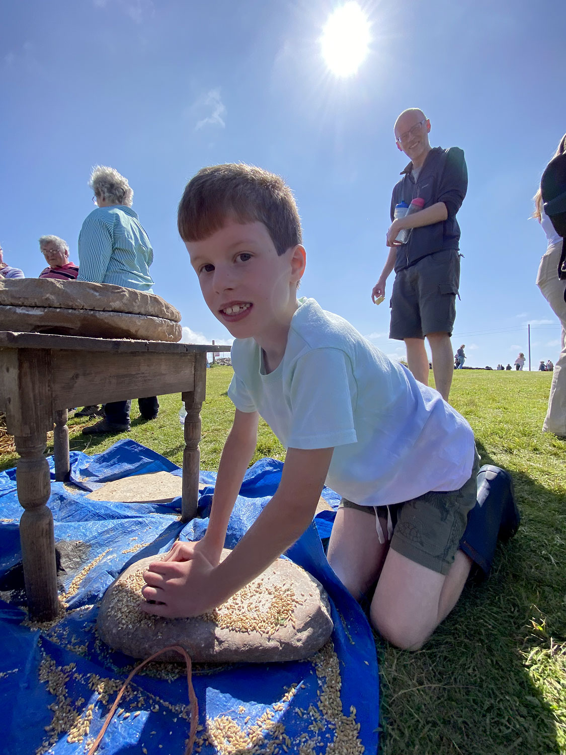 Calum from Essex grinding grain on a saddle quern. (📷 Jo Bourne) – The ...